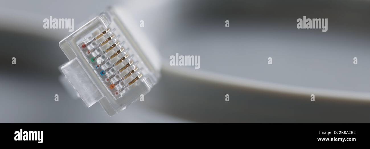 Internet connector on grey background, focus on cable with plastic clip ...