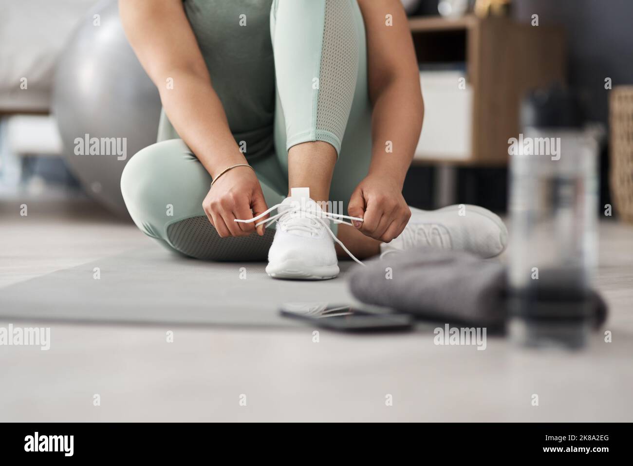 Get ready to get started. Closeup shot of an unrecognisable woman tying her shoelaces while ...