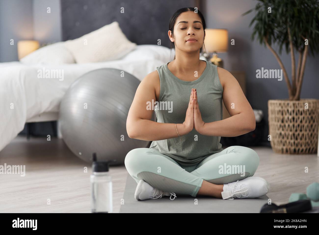 Its all about gaining balance. a sporty young woman meditating at home ...