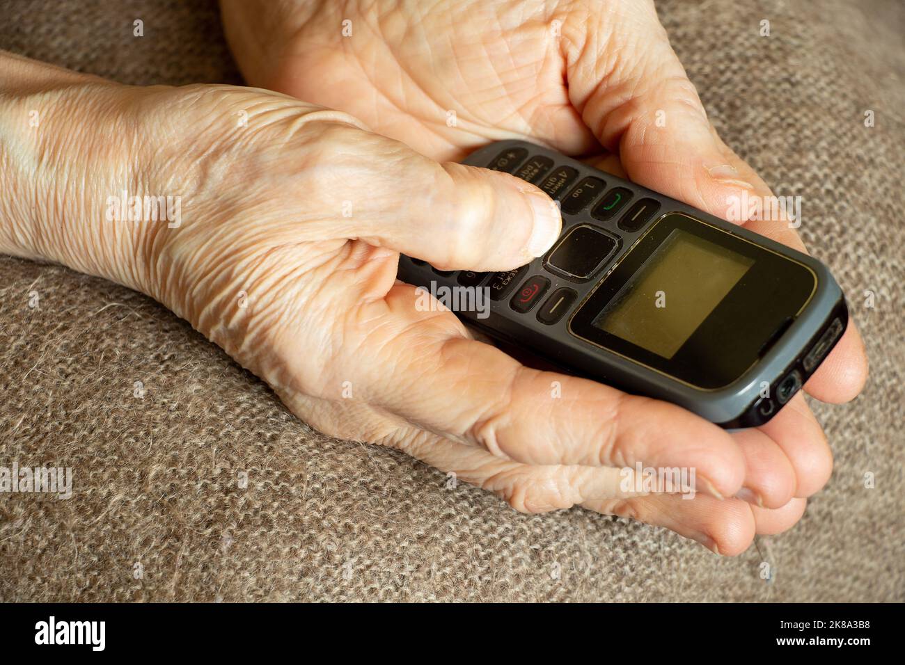 old woman's hands hold push-button telephone at home, pensioner with ...