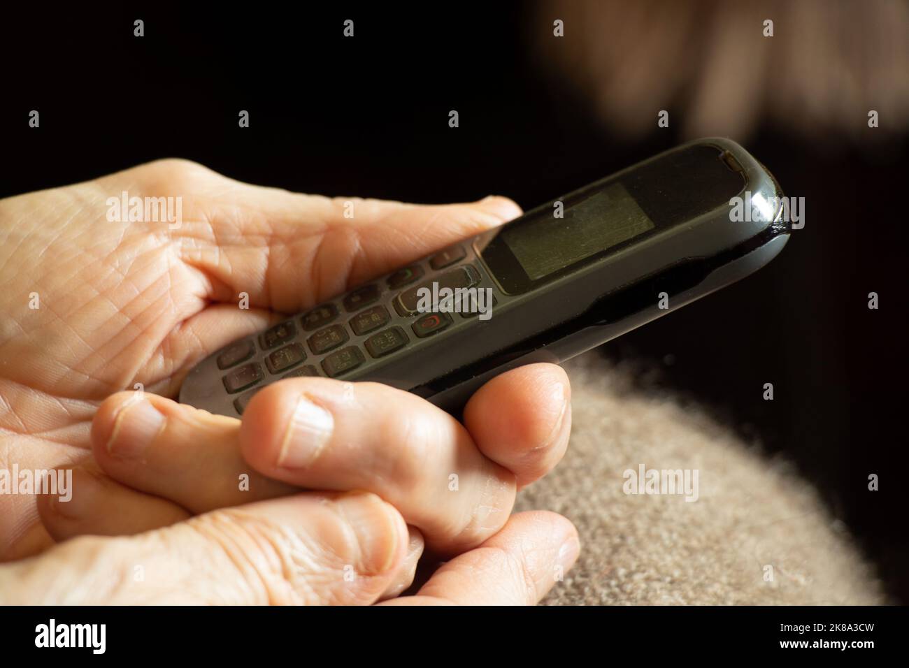 old woman's hands hold push-button telephone at home, pensioner with ...