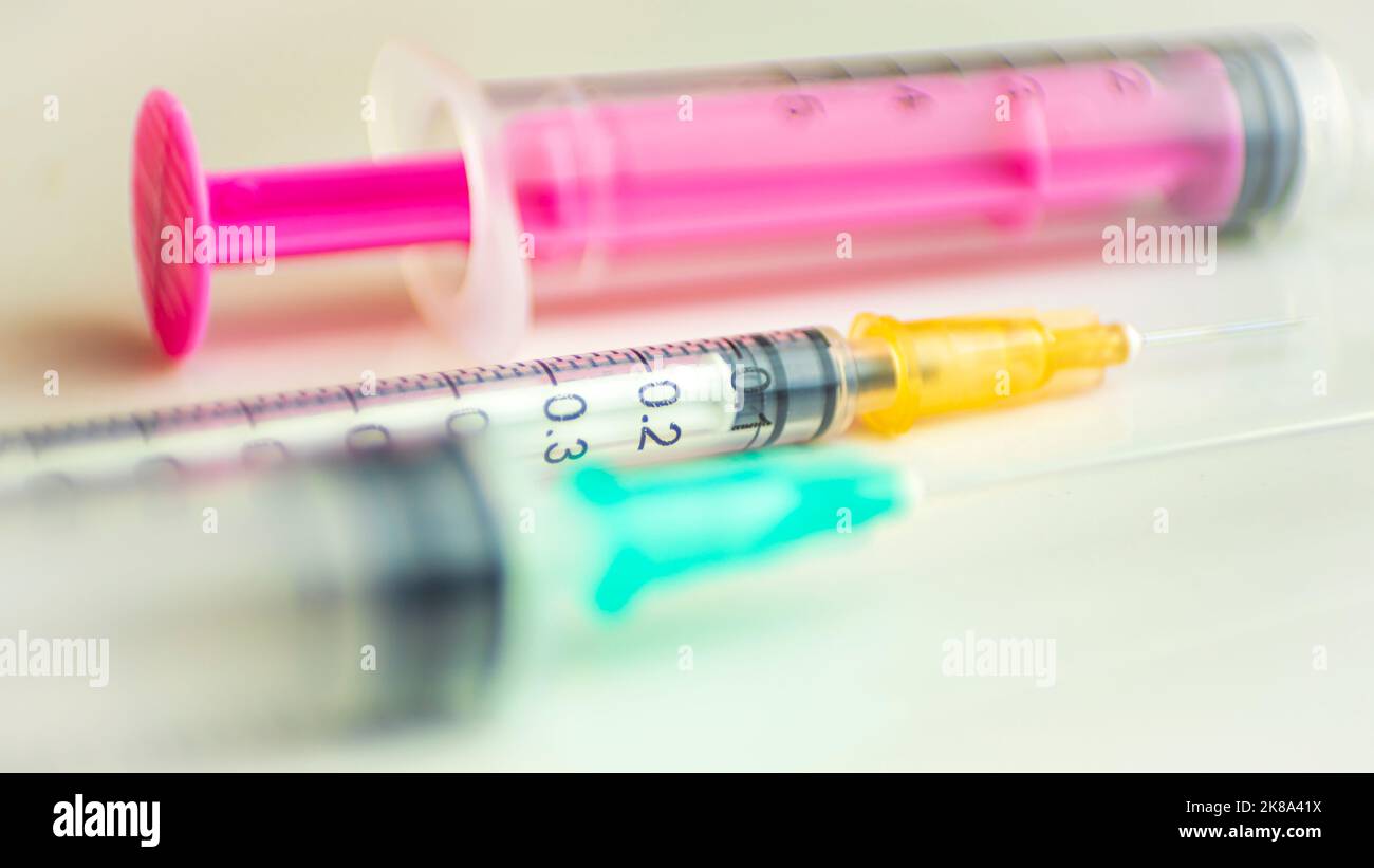 Three syringes of different thicknesses and colors on a well-lit white ...