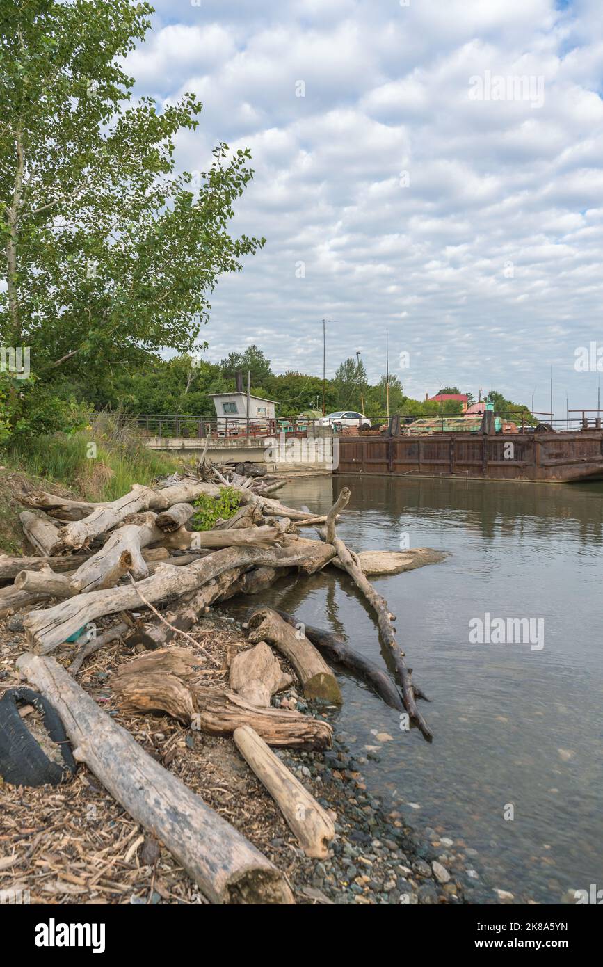 snags dump at teh river Ob shore with part of rusty barge platform ...