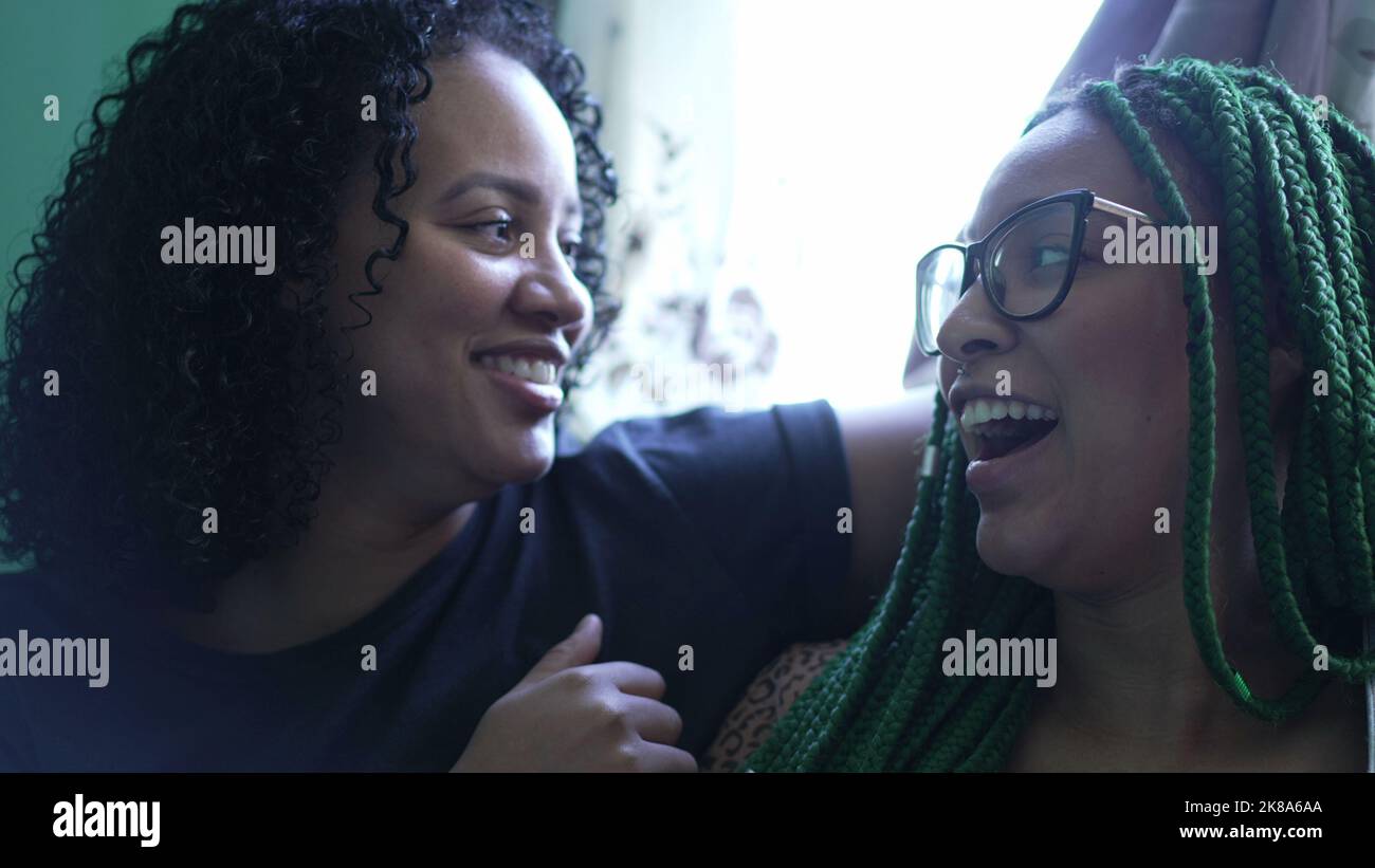 Candid female sisters at home in conversation. Two young hispanic black ...
