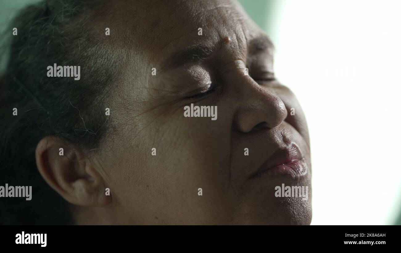 Contemplative senior South American woman closing eyes in meditation ...