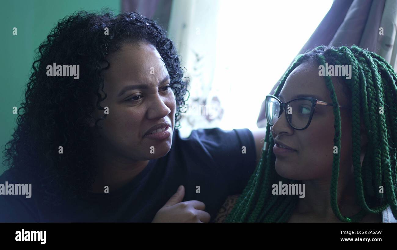 Candid female sisters at home in conversation. Two young hispanic black ...