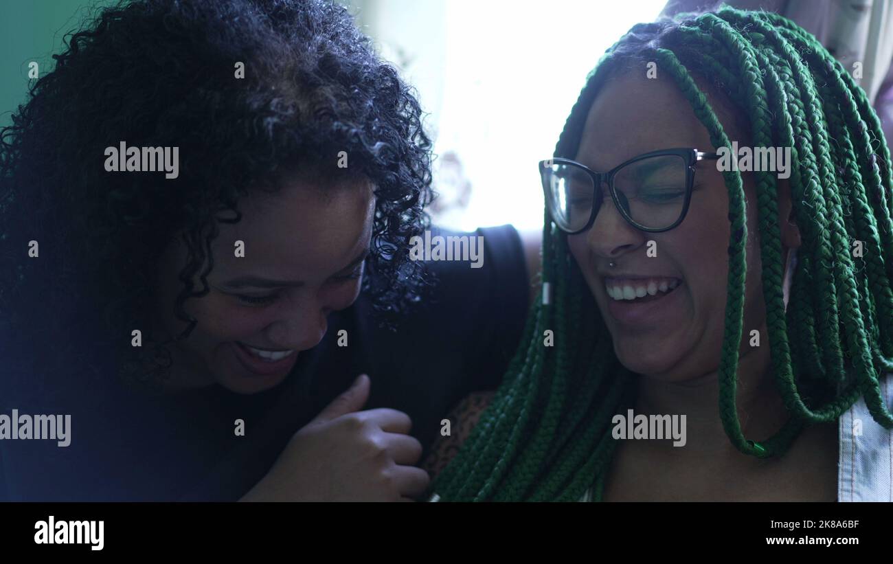Candid female sisters at home in conversation. Two young hispanic black ...