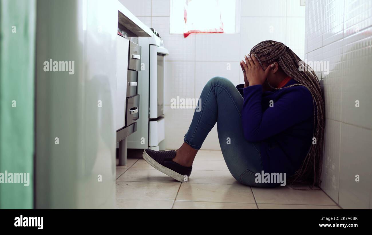 Desperate young woman losing hope sitting on kitchen floor suffering ...