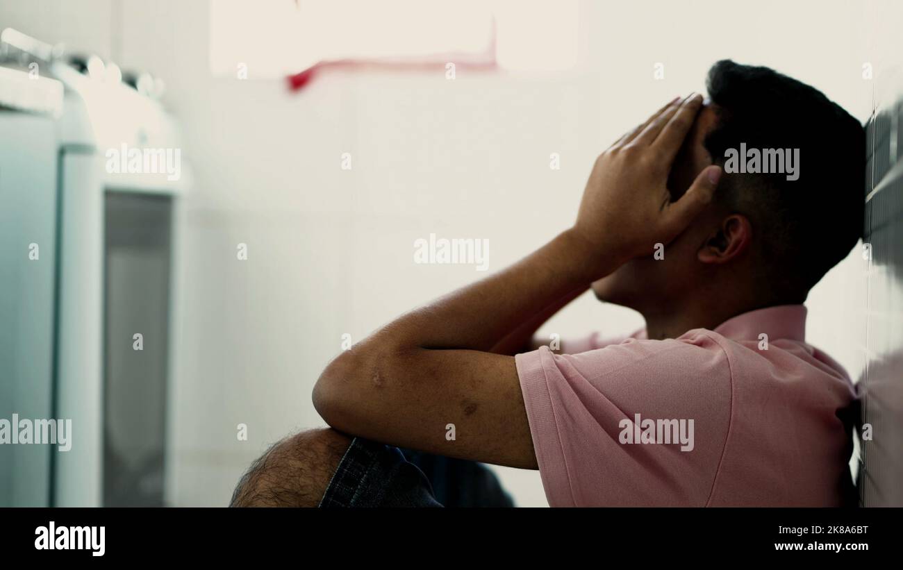 Depressed man sitting on floor. Sad unhappy person holding his forehead ...