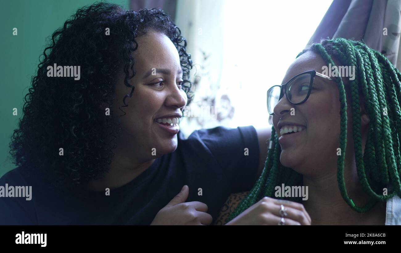 Candid female sisters at home in conversation. Two young hispanic black ...