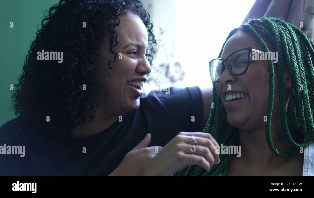 Candid female sisters at home in conversation. Two young hispanic black ...