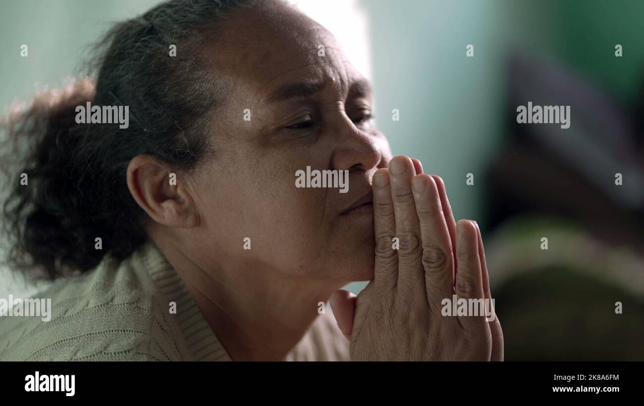 Older woman praying to God at home. One hispanic senior lady in prayer ...