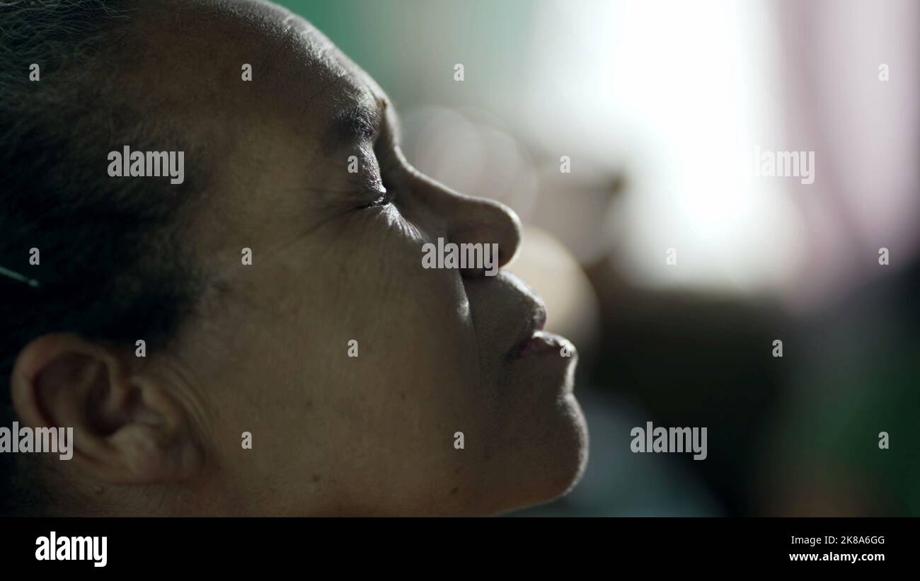 One contemplative hispanic senior woman closing eyes in meditation ...