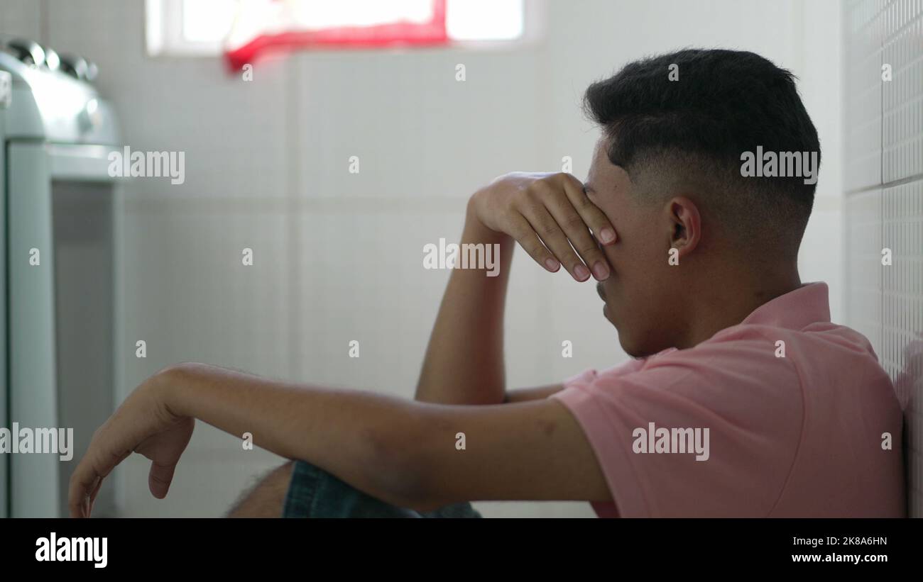 One depressed hispanic young man in mental distress sitting on kitchen ...