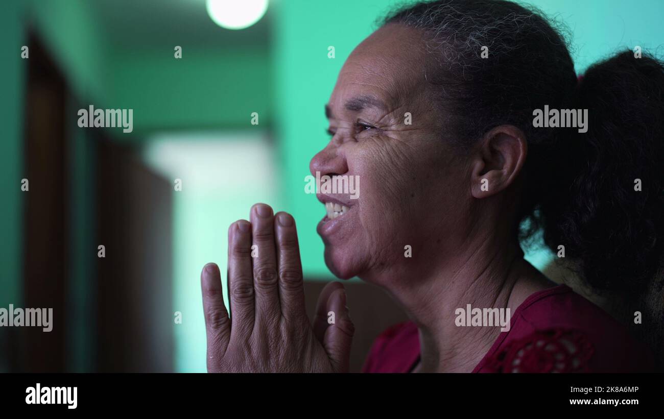 Hopeful mature hispanic senior woman praying smiling Stock Photo - Alamy