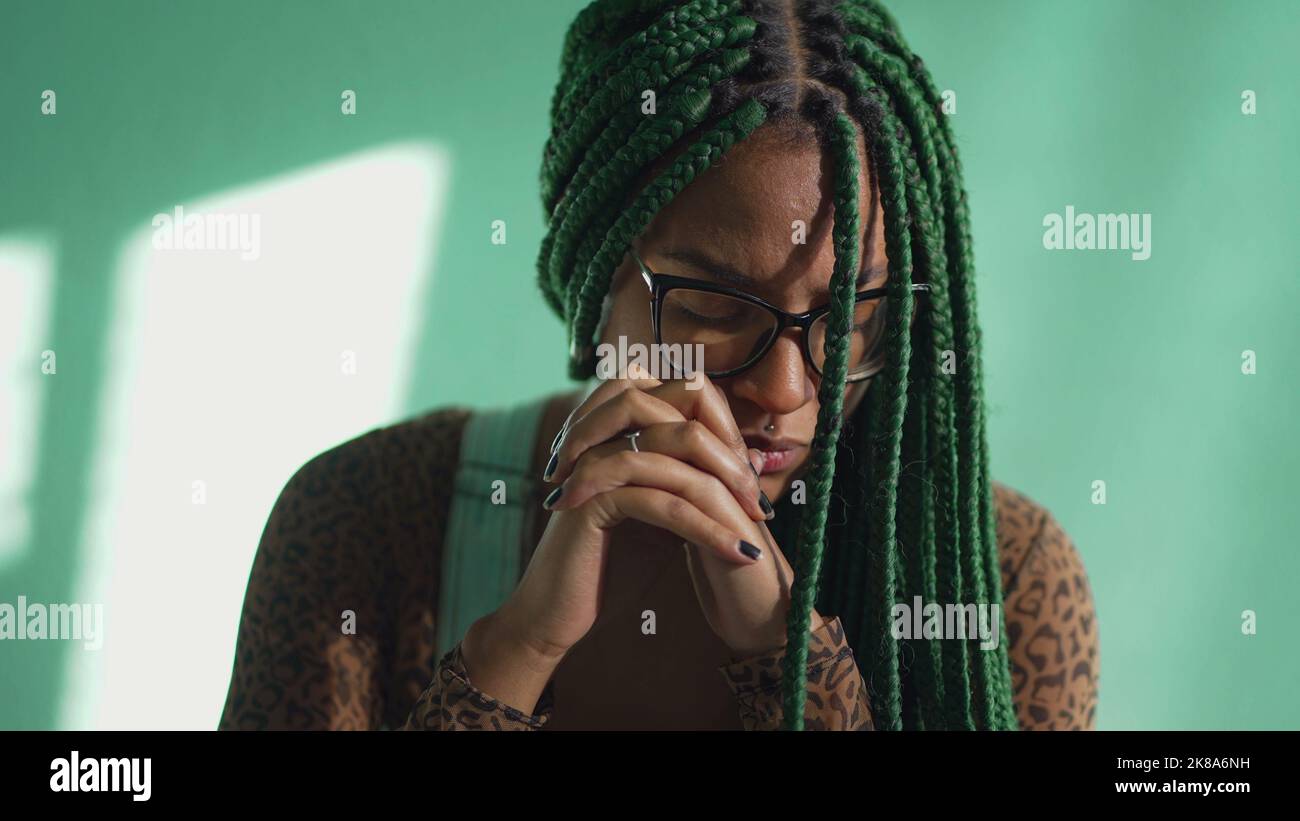 Pensive African American in contemplation praying to God at home. One ...