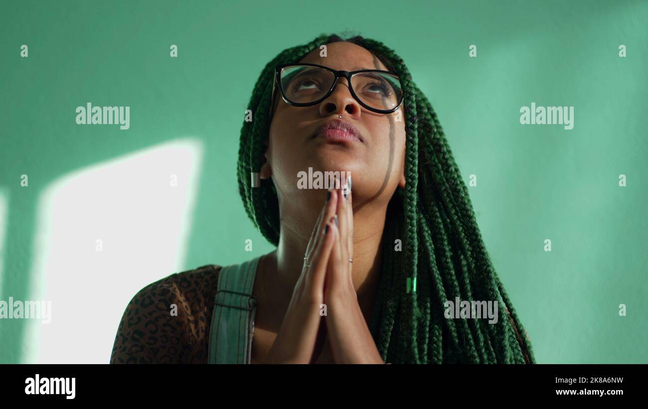 Pensive African American in contemplation praying to God at home. One ...
