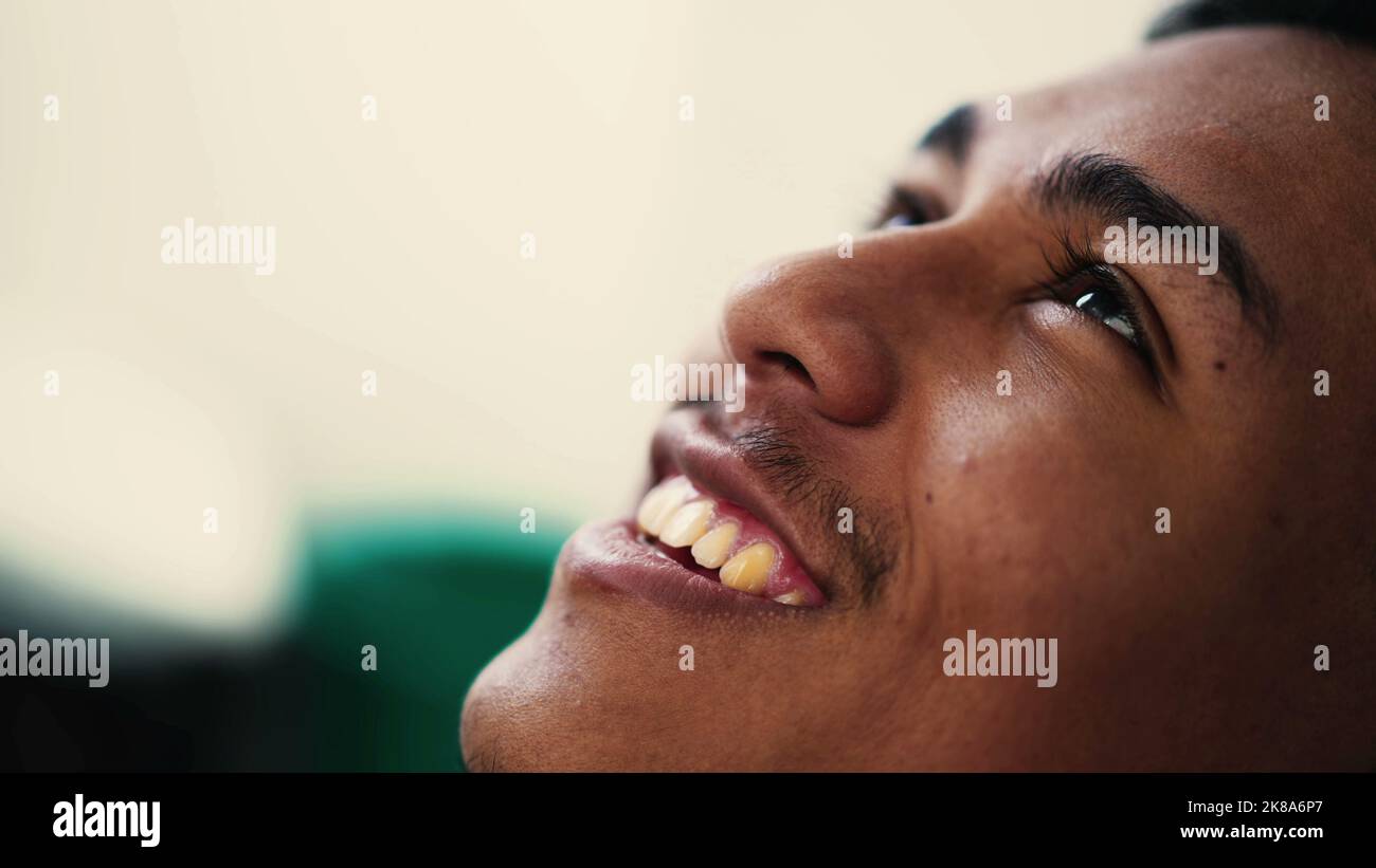 One young hispanic man opening eyes to sky smiling having HOPE and ...
