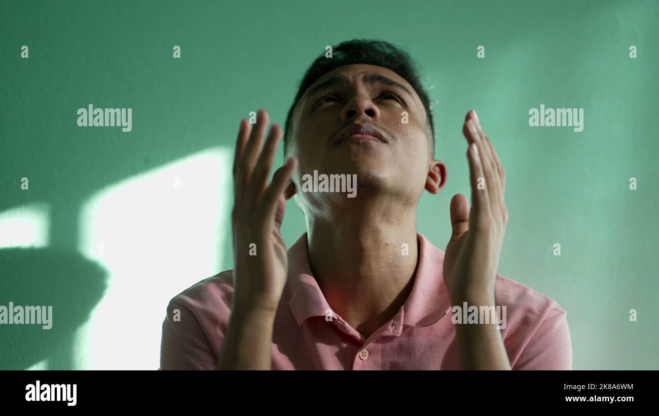 Religious hispanic young man praying to God in transcendence. South ...