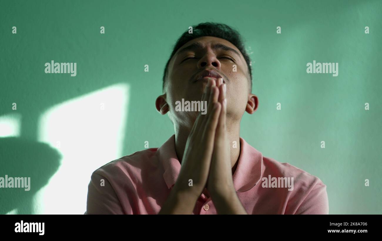 Religious hispanic young man praying to God in transcendence. South ...