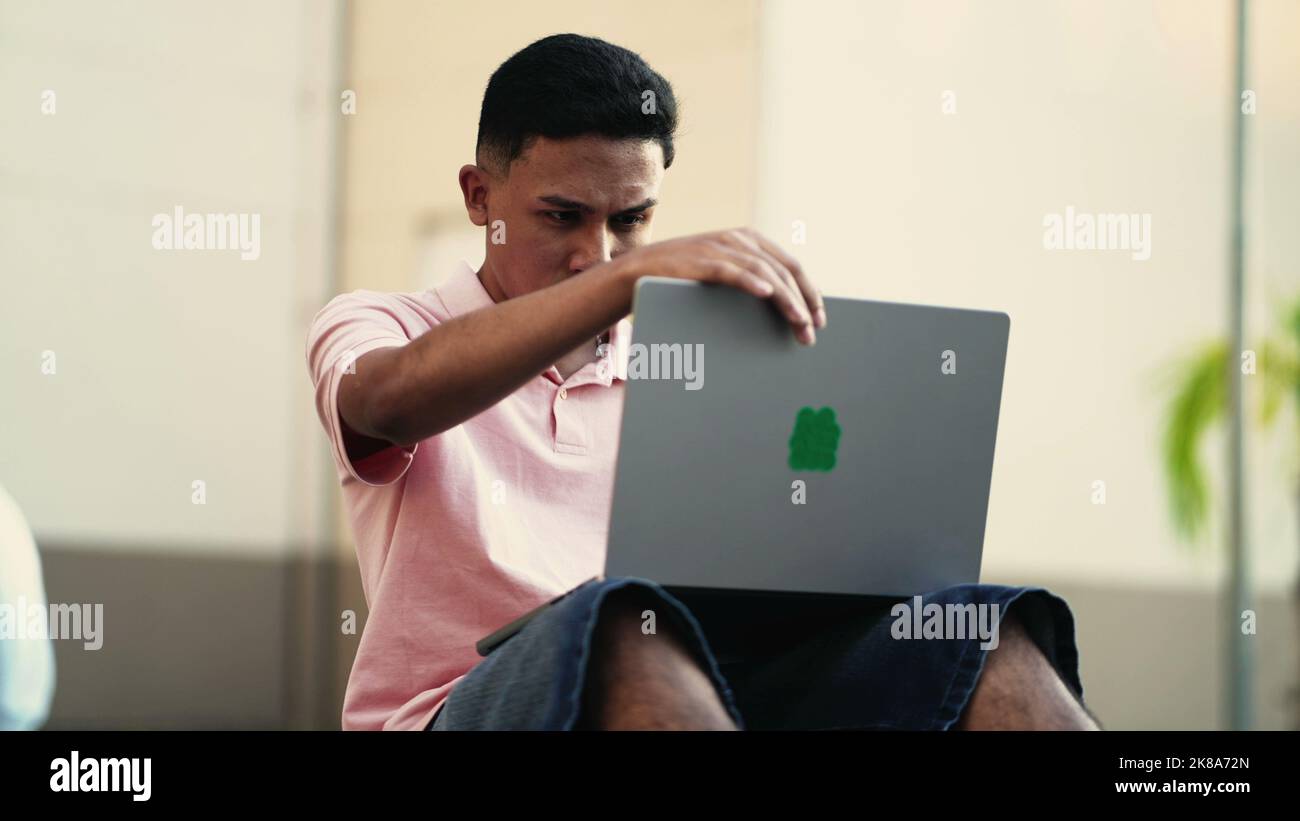 A hispanic young man turning computer ON. Person opening laptop sitting ...