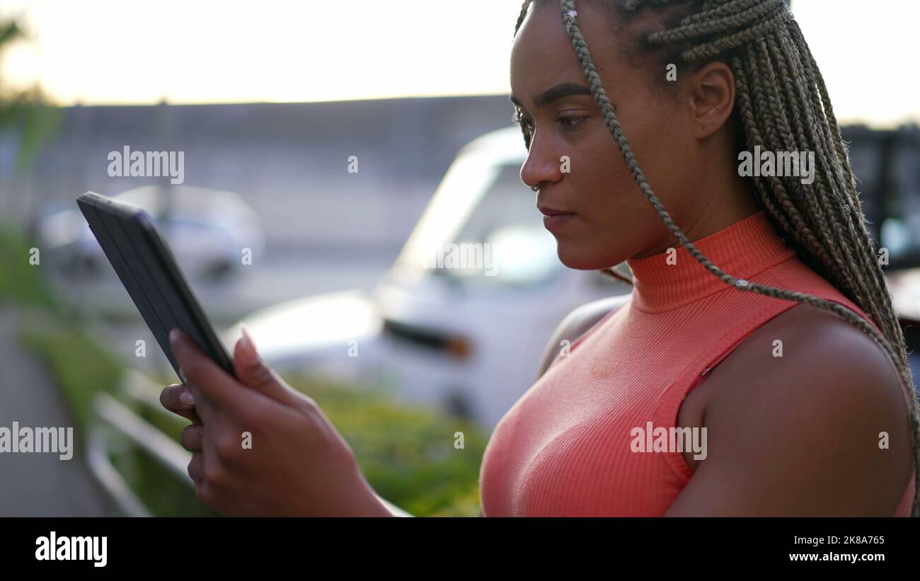 A black young woman standing outside holding tablet device Stock Photo ...