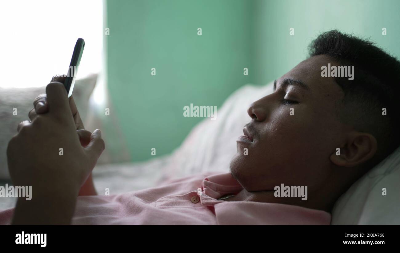 One hispanic person in bedroom looking at smartphone device. good for ...