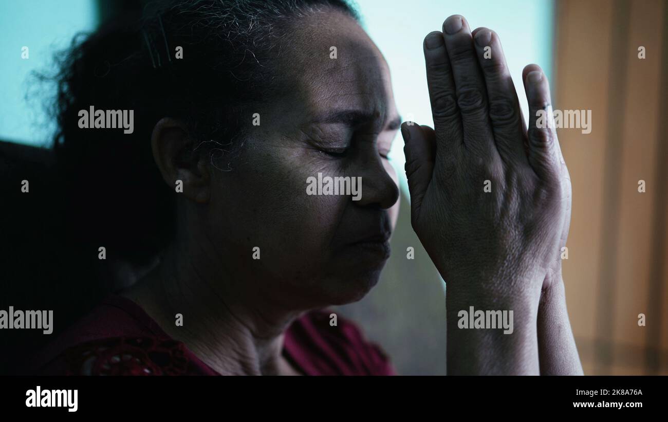 One hispanic senior woman praying to God. A religious older South ...