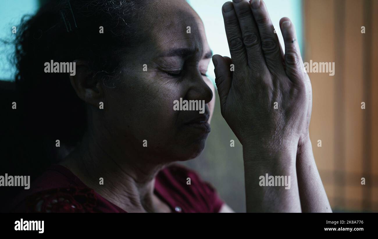 One hispanic senior woman praying to God. A religious older South ...