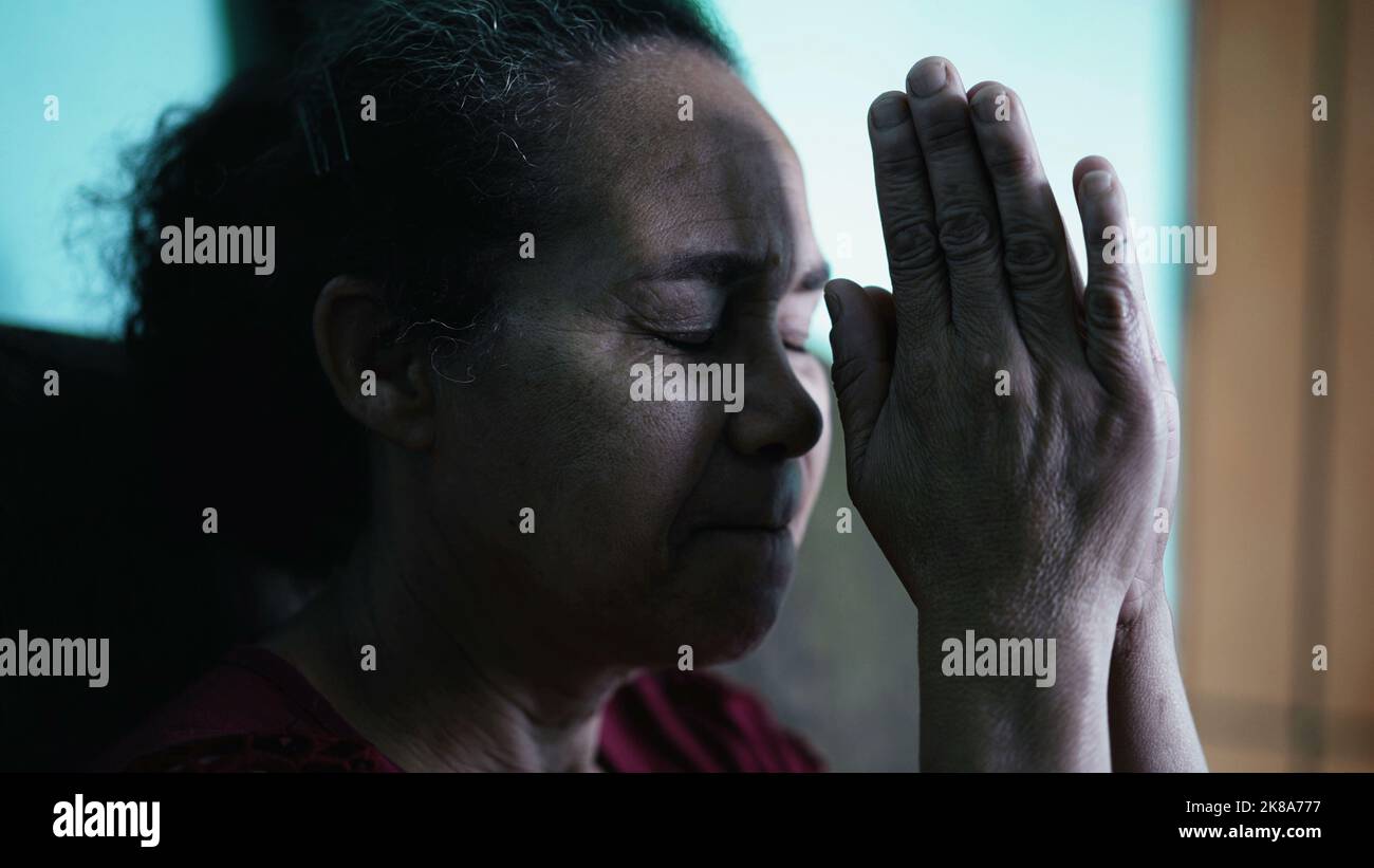 One hispanic senior woman praying to God. A religious older South ...