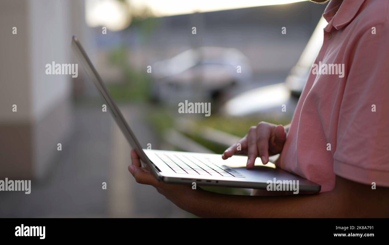 Closeup person hands holding laptop standing outdoors. Young man using ...