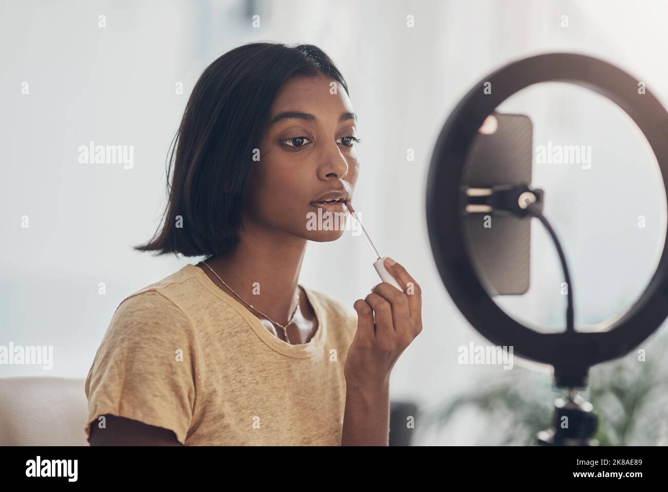 My go to gloss for that extra glam. a young woman applying makeup while ...