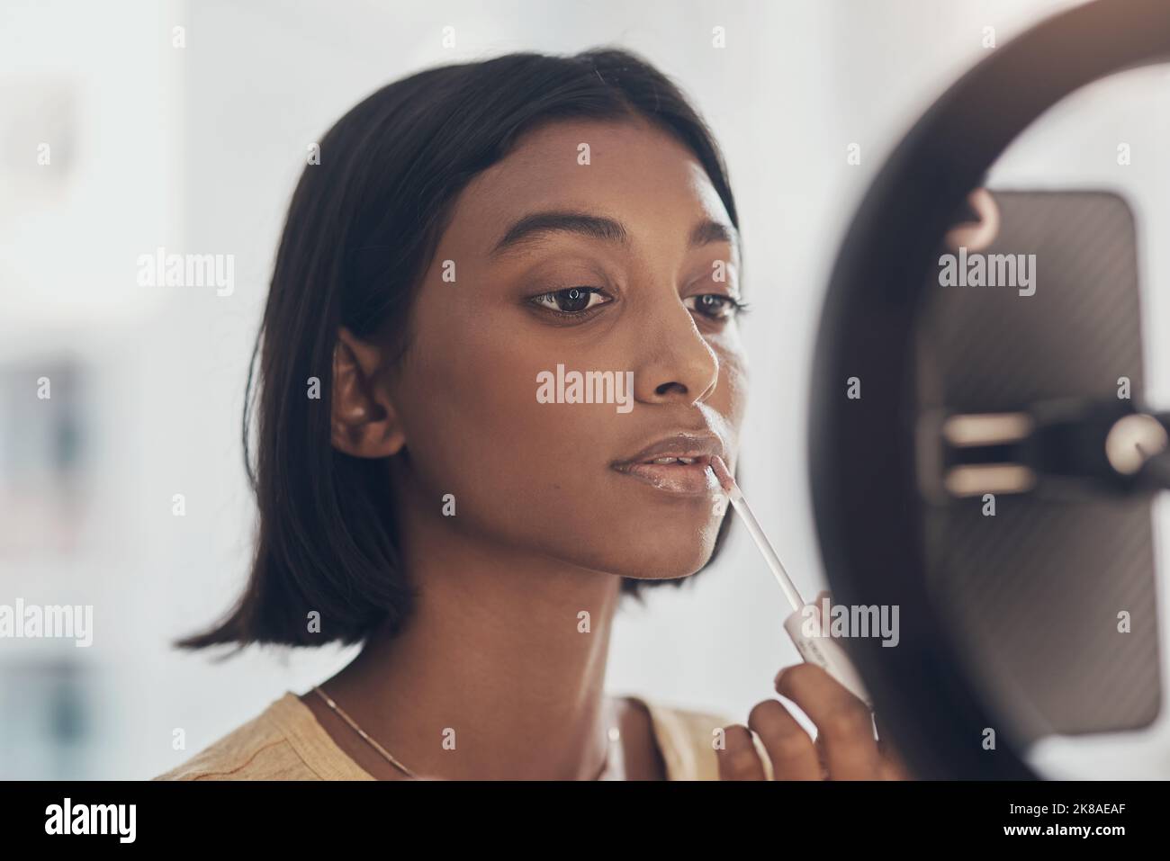 Take her beauty tips and glow with it. a young woman applying makeup ...