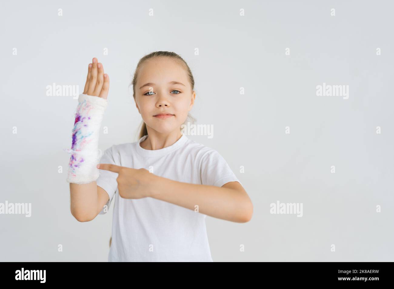 Portrait of cheerful little girl showing with index finger to broken ...