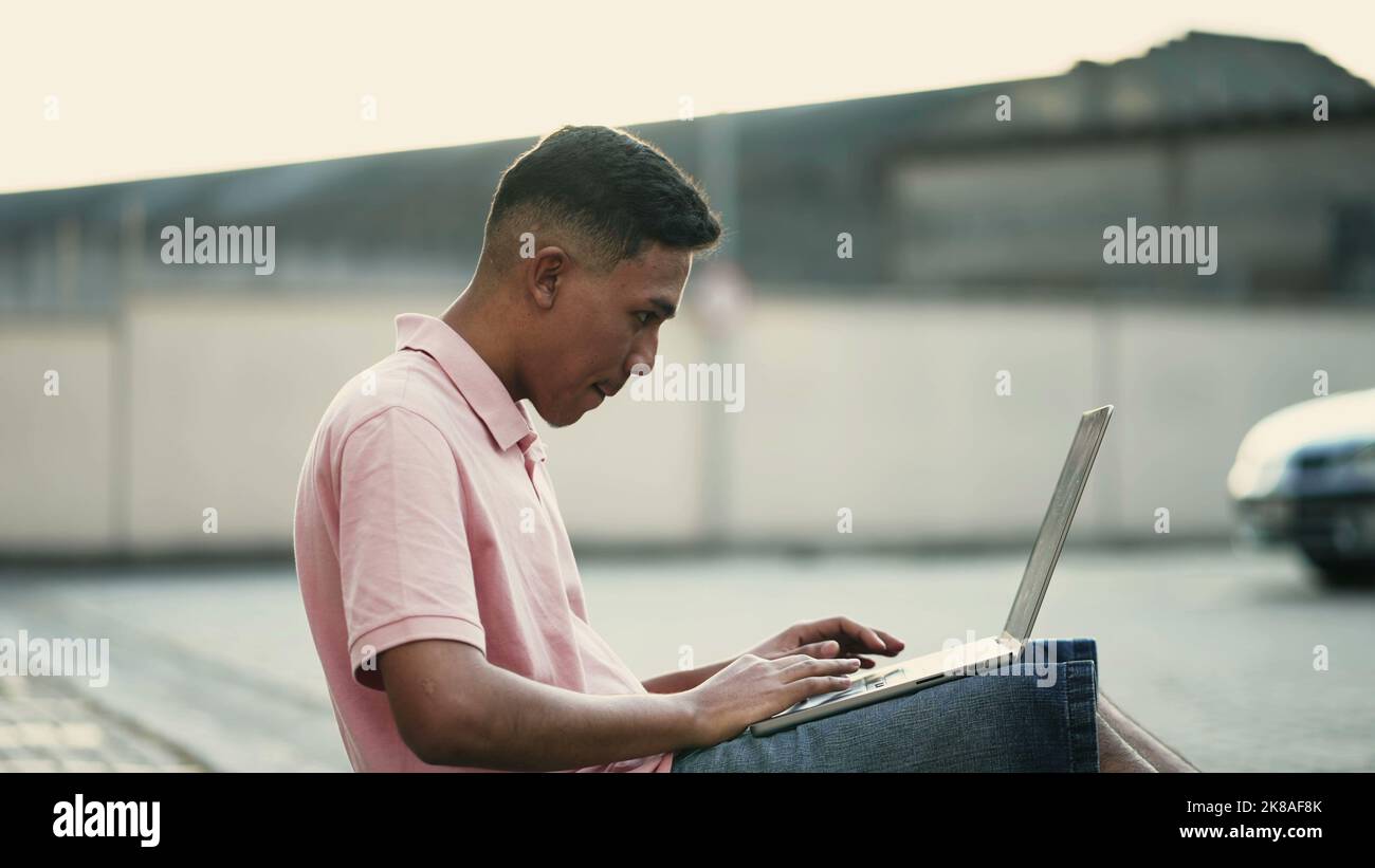 Young Brazilian man opening laptop computer in remote work or study ...