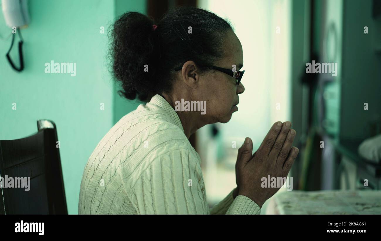 One hopeful black senior woman praying to God. A spiritual latin South ...