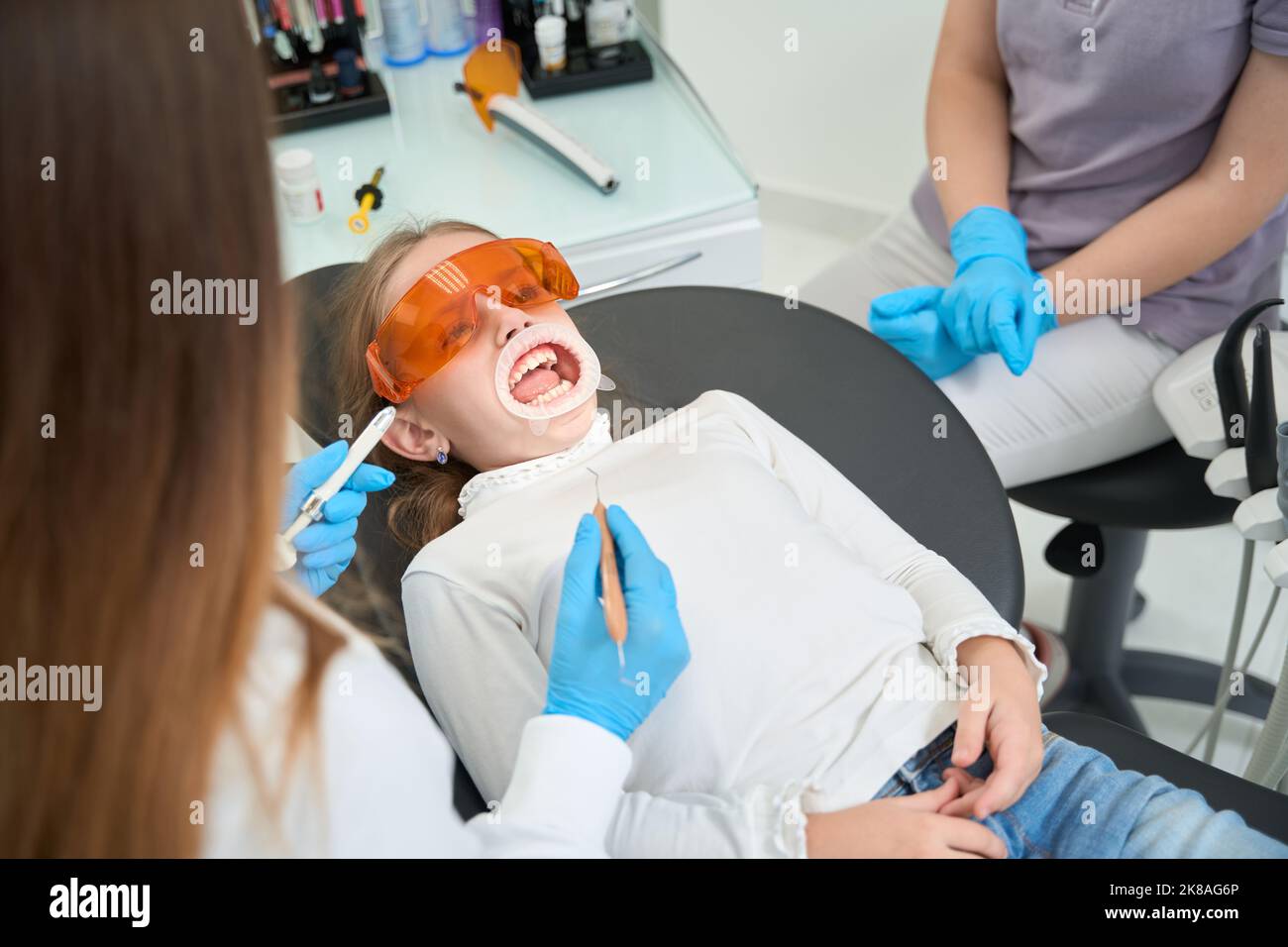 Pre-teen girl surrounded by dental staff before teeth examination Stock ...