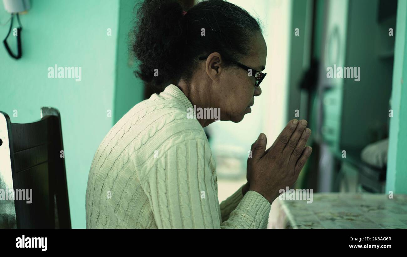 One hopeful black senior woman praying to God. A spiritual latin South ...