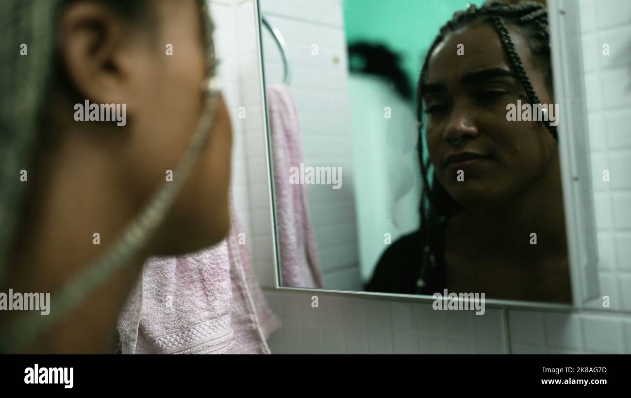 One millennial black latina girl looking at herself in the mirror ...