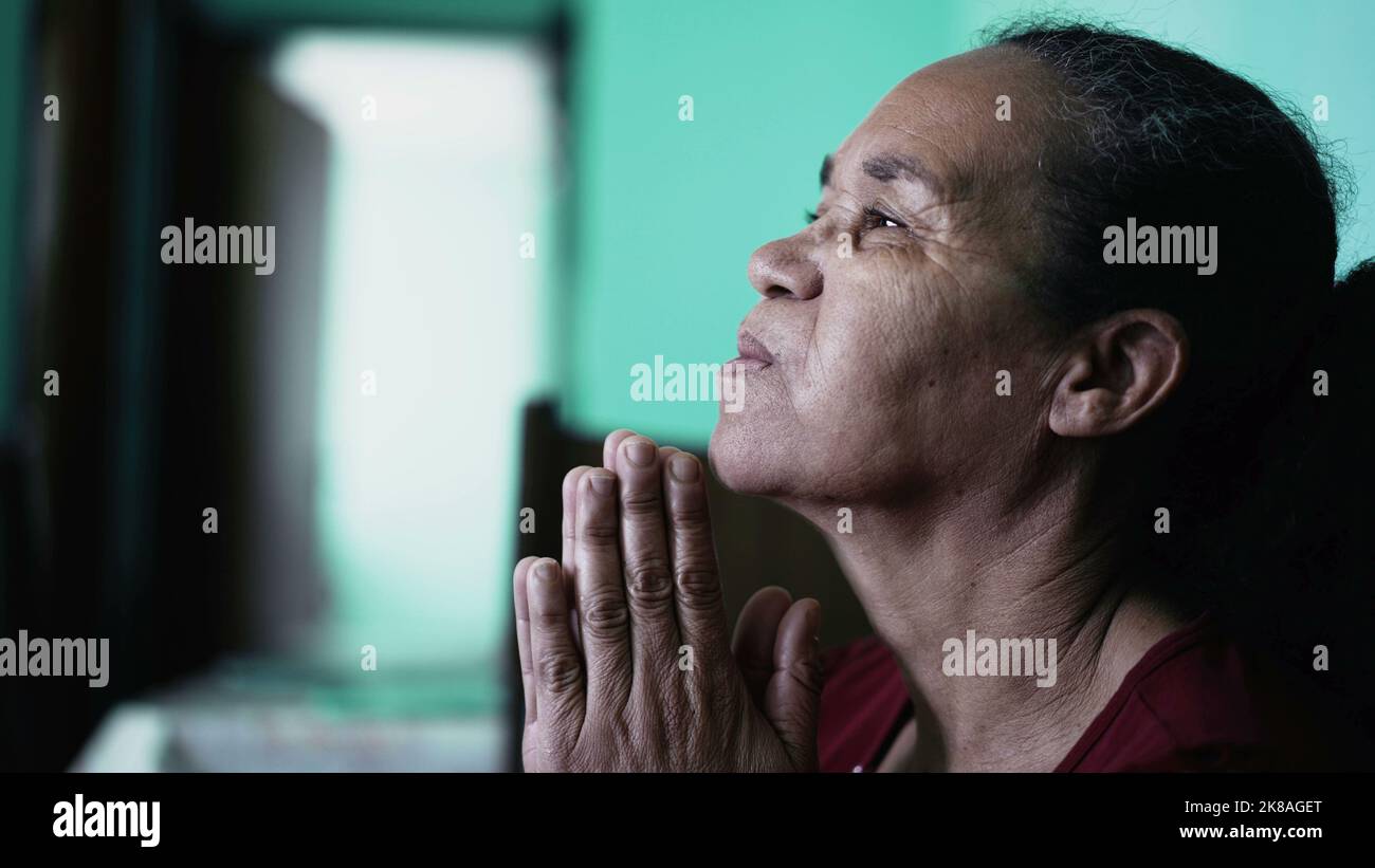 One senior hispanic woman praying to God. A Brazilian older person ...