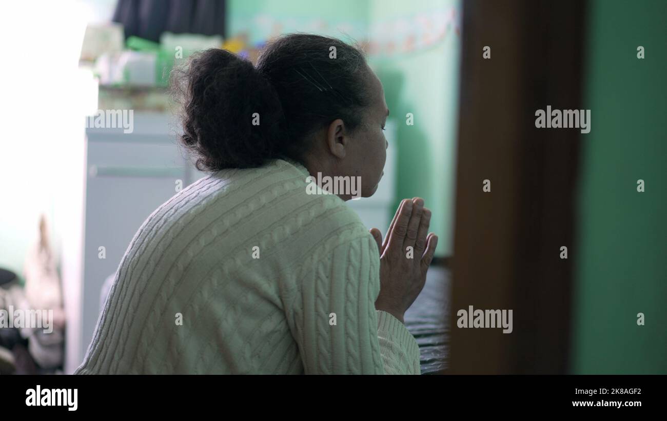 One senior woman praying at home by bedside. A spiritual older black ...