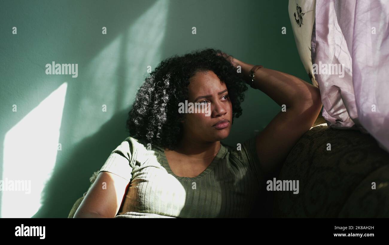 Thoughtful person thinking about life looking out apartment window in ...