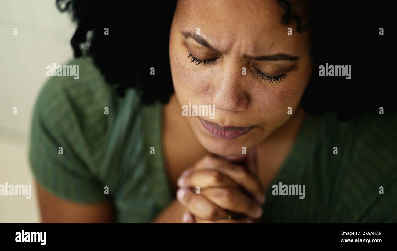 A faithful young black woman praying to God. Religious South American ...