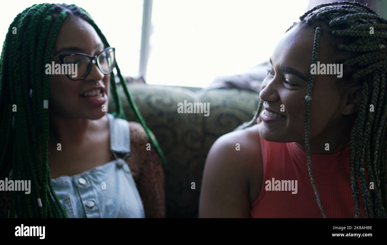 Two young hispanic black latina women speaking in conversation at home ...