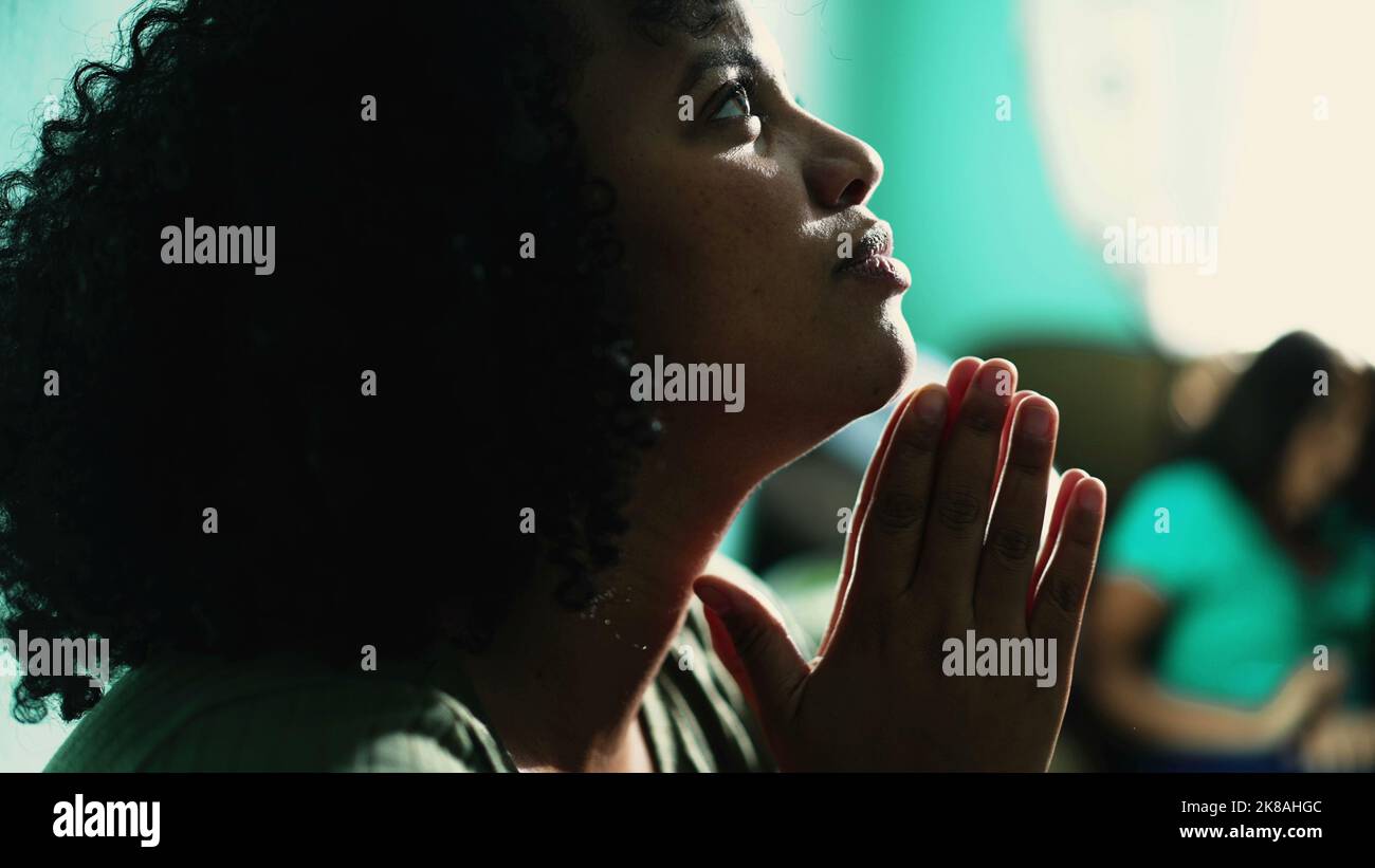 African American woman praying to God. A spiritual black hispanic girl ...
