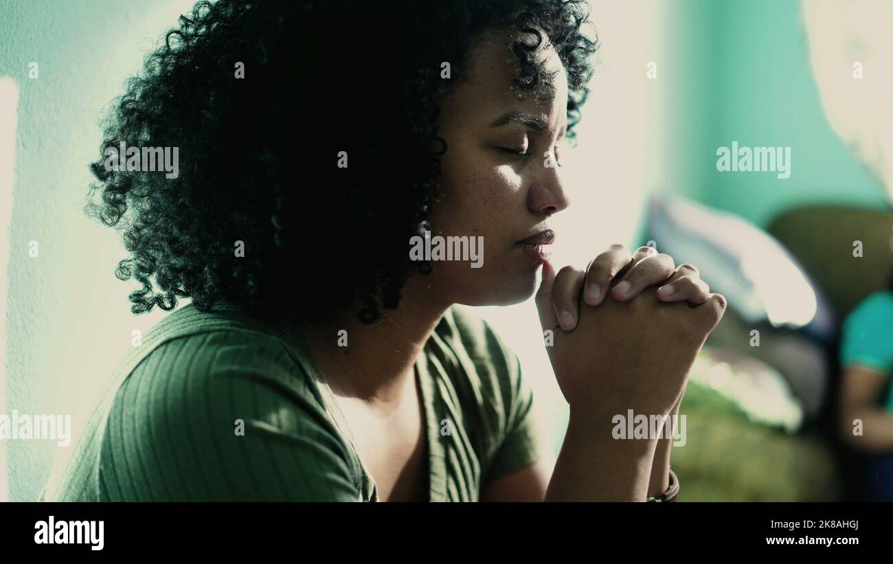 African American woman praying to God. A spiritual black hispanic girl ...