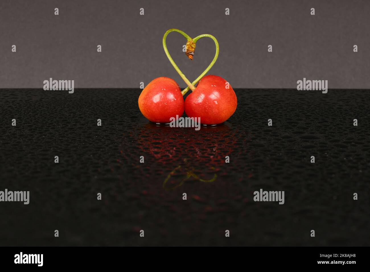 Two heart-shaped cherries on a black acrylic background. High ...