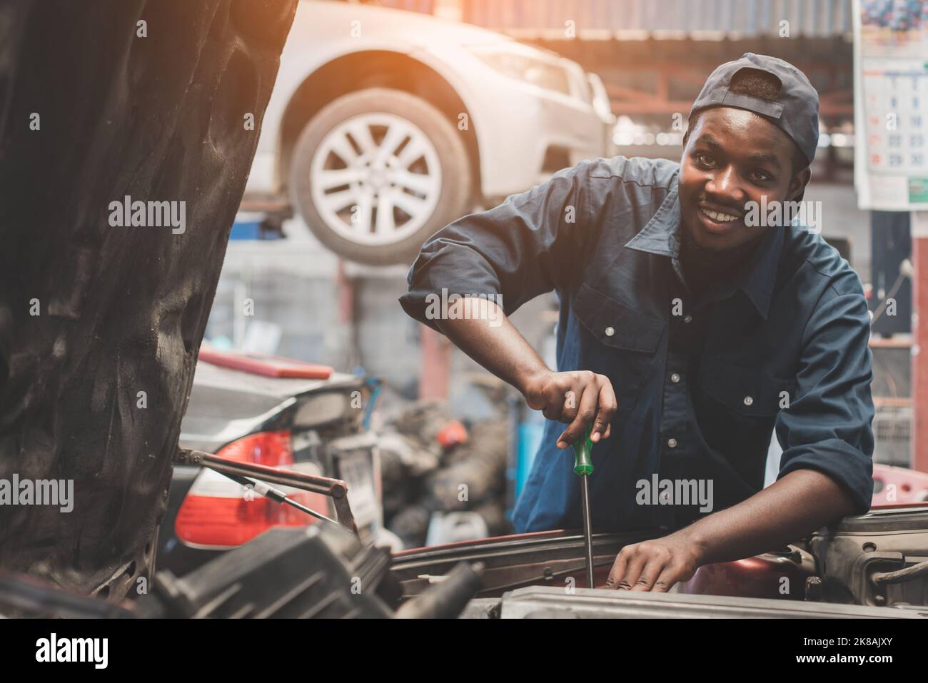 African man mechanic in uniform with tools and wrenches standing at the ...