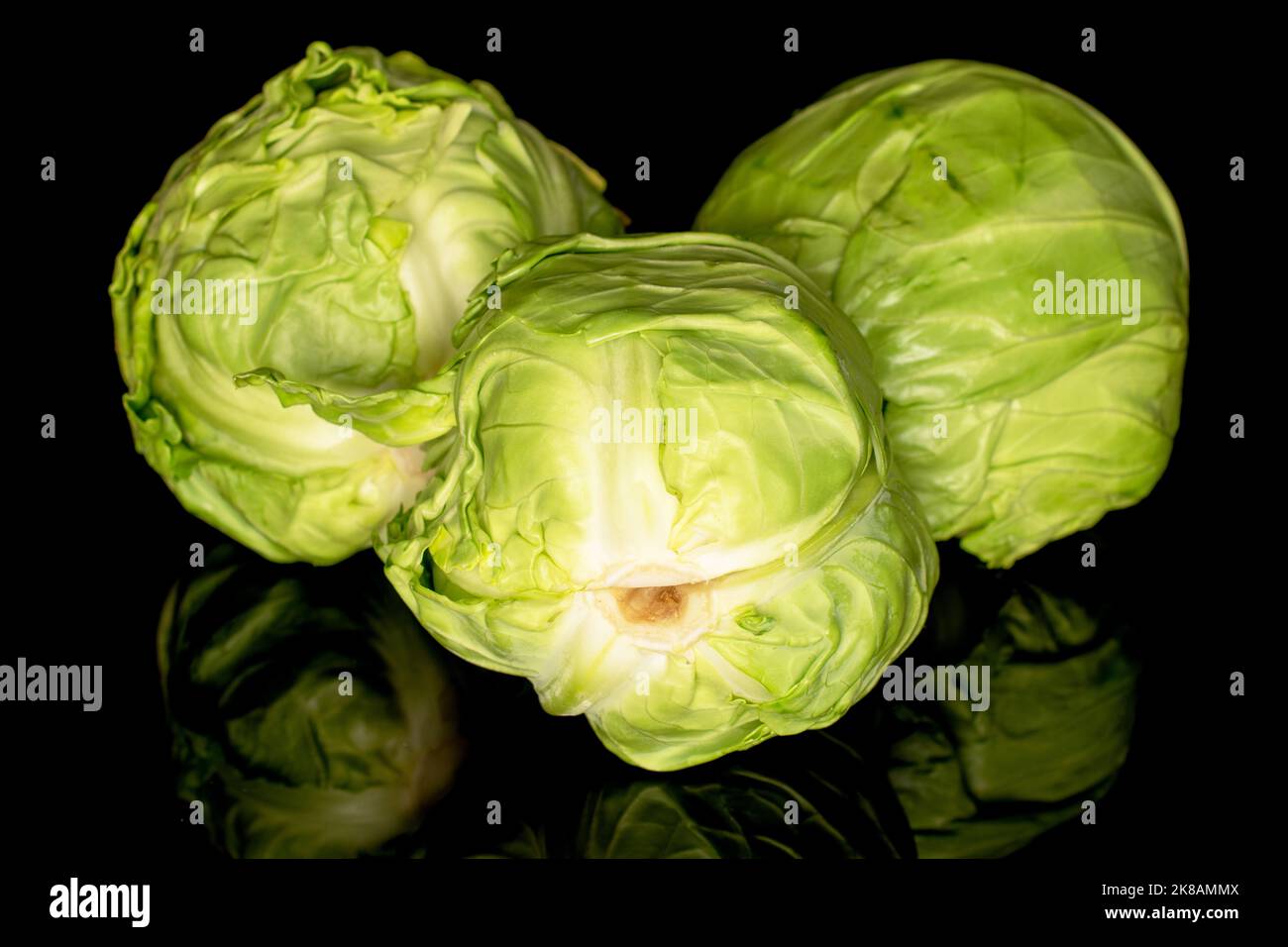 Three heads of fresh cabbage, macro, isolated on a black background ...