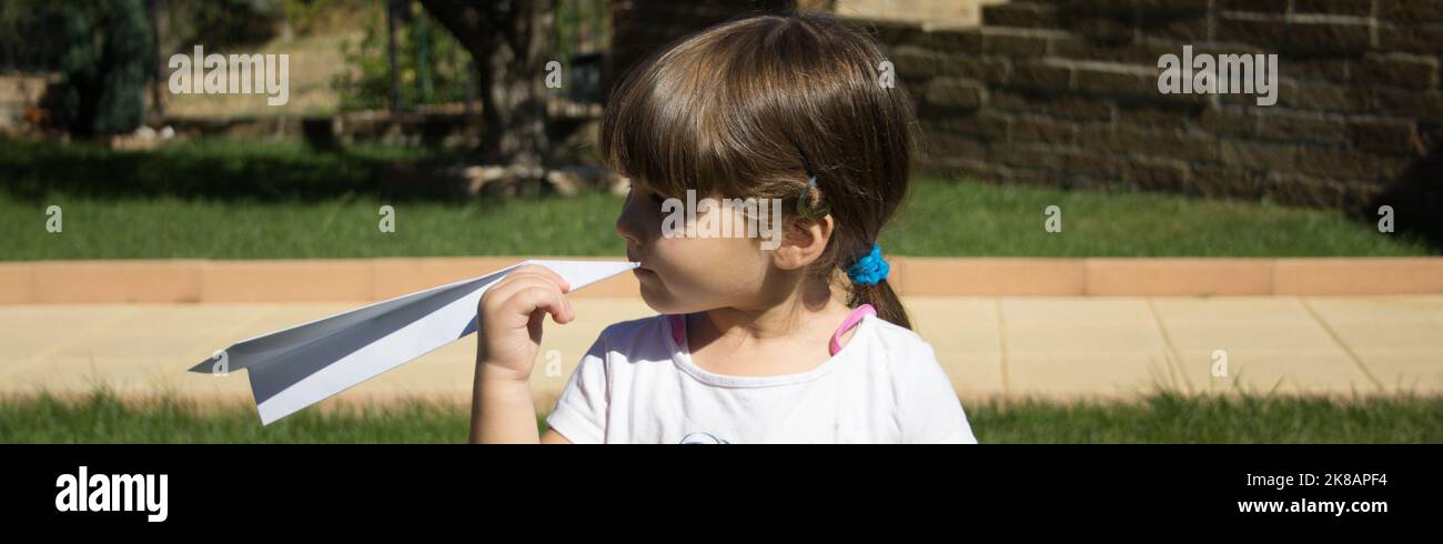 Picture of an adorable little girl playing a little paper airplane ...